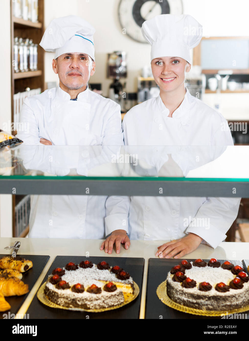 Experienced man and woman staff offering cakes and buns in bakery Stock ...
