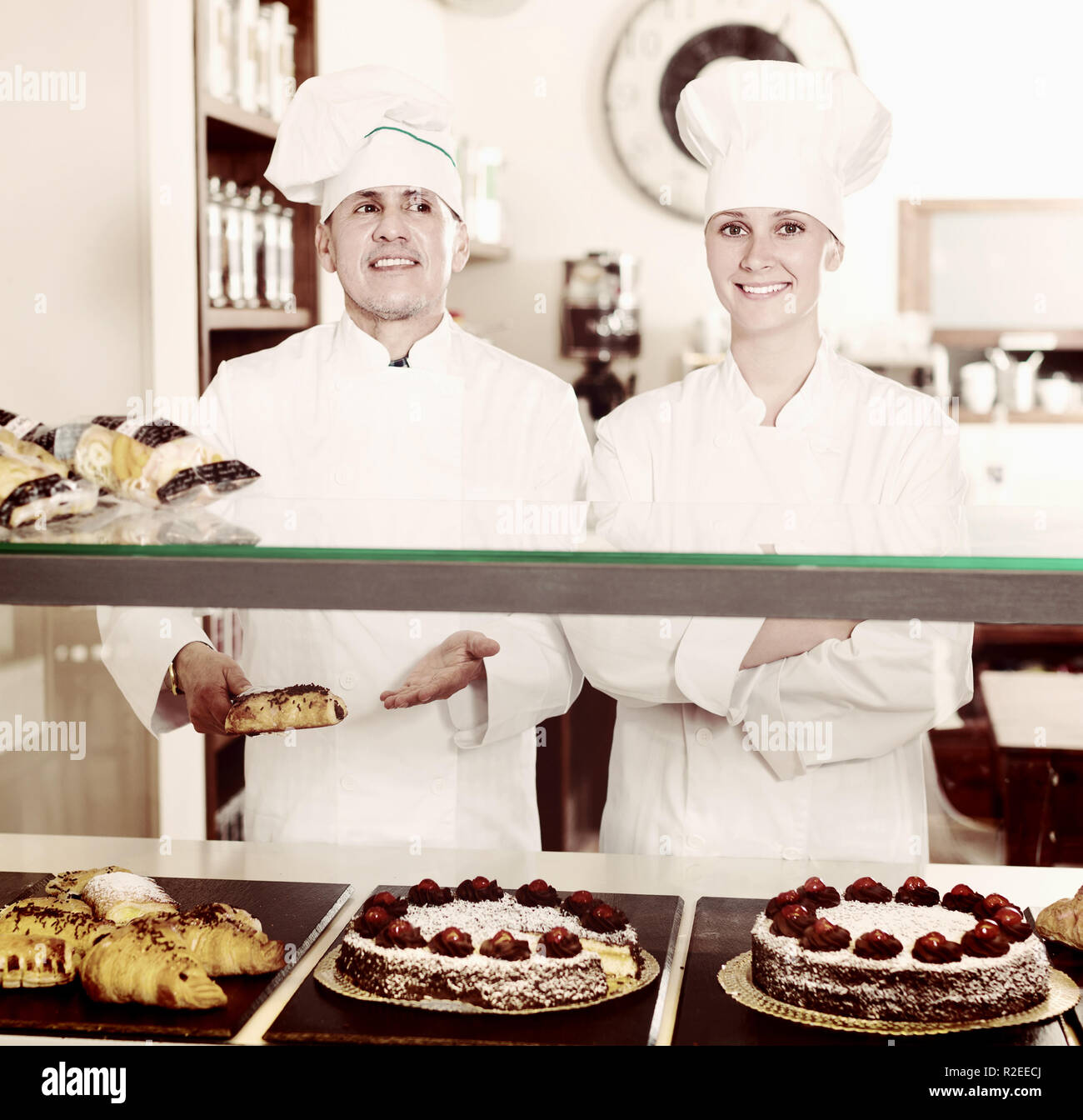Smiling male and female bakery employees with tasty roll and cakes on ...