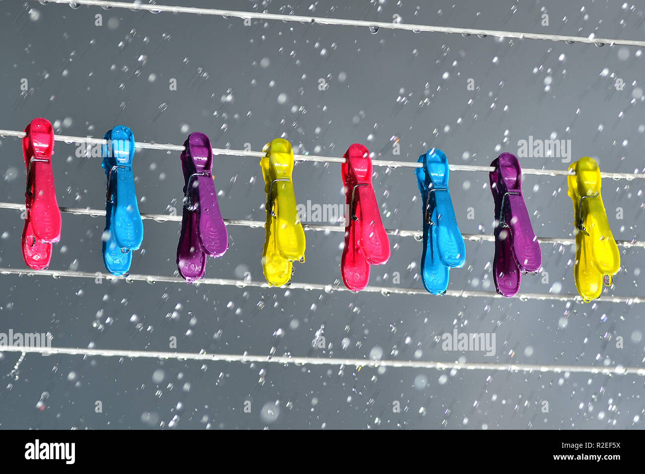 Colourful pegs on washing line in the rain Stock Photo - Alamy