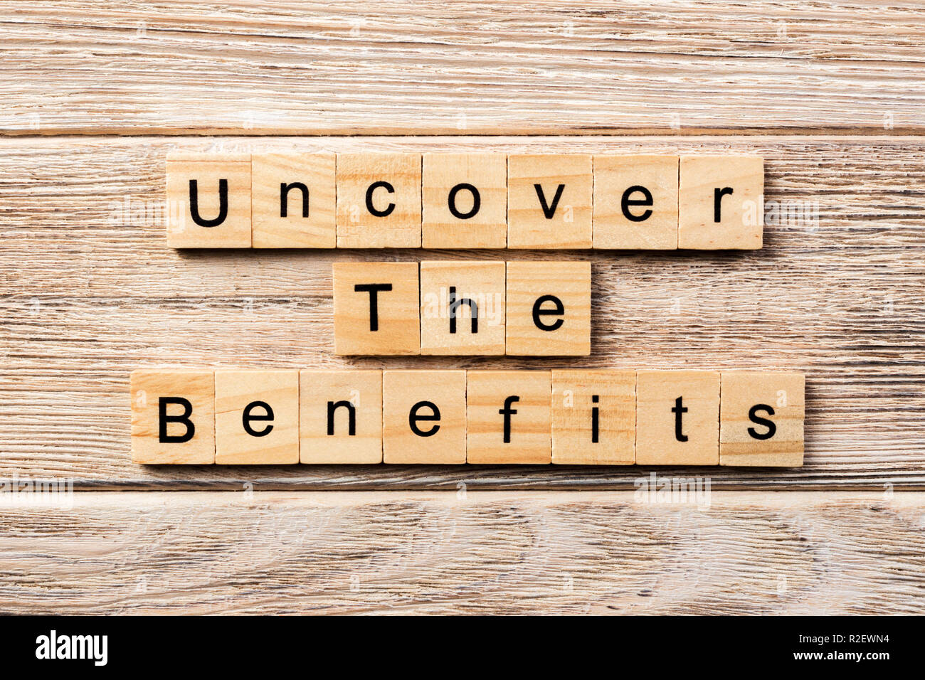 uncover the benefits word written on wood block. uncover the benefits text on table, concept ...