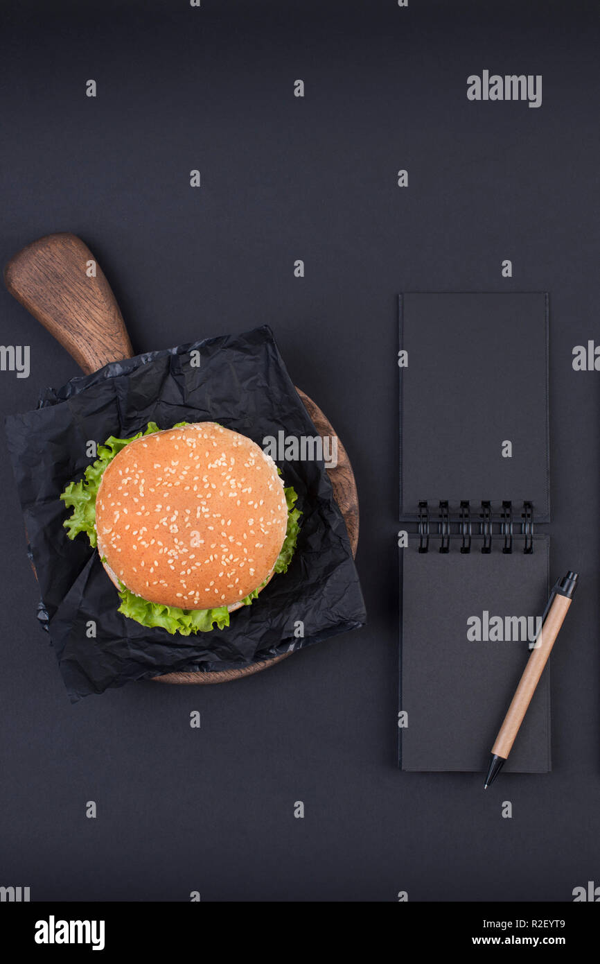 Big hamburger with sesame seeds on a black background. Fast food and ...