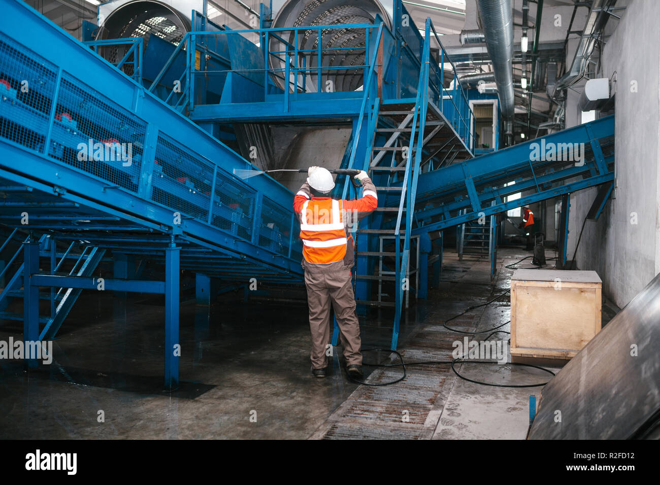The worker washes the equipment at the waste sorting plant. Waste ...