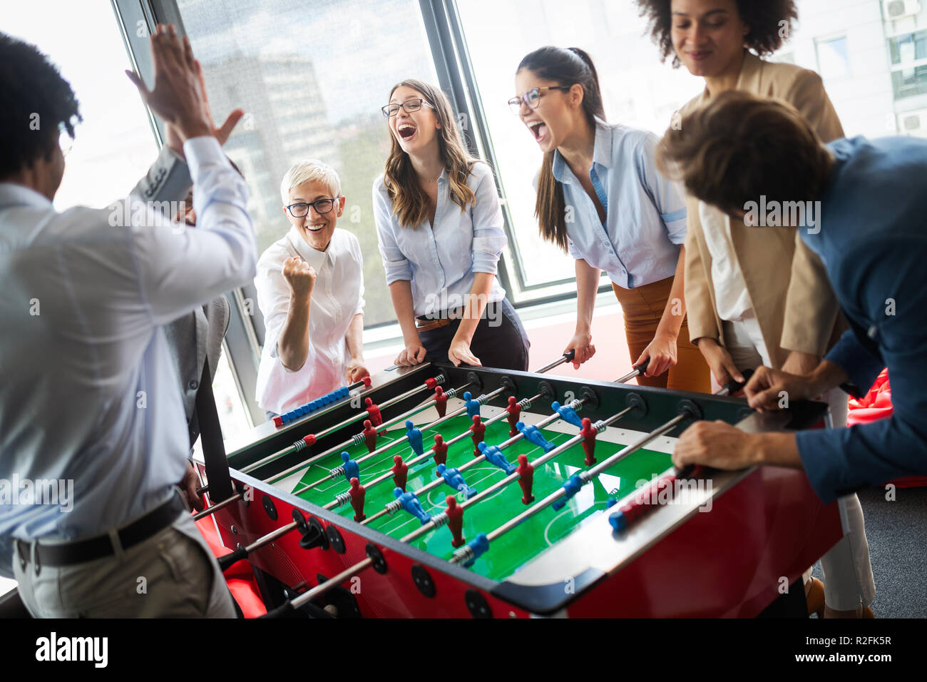 Employees playing table soccer indoor game in the office during break ...
