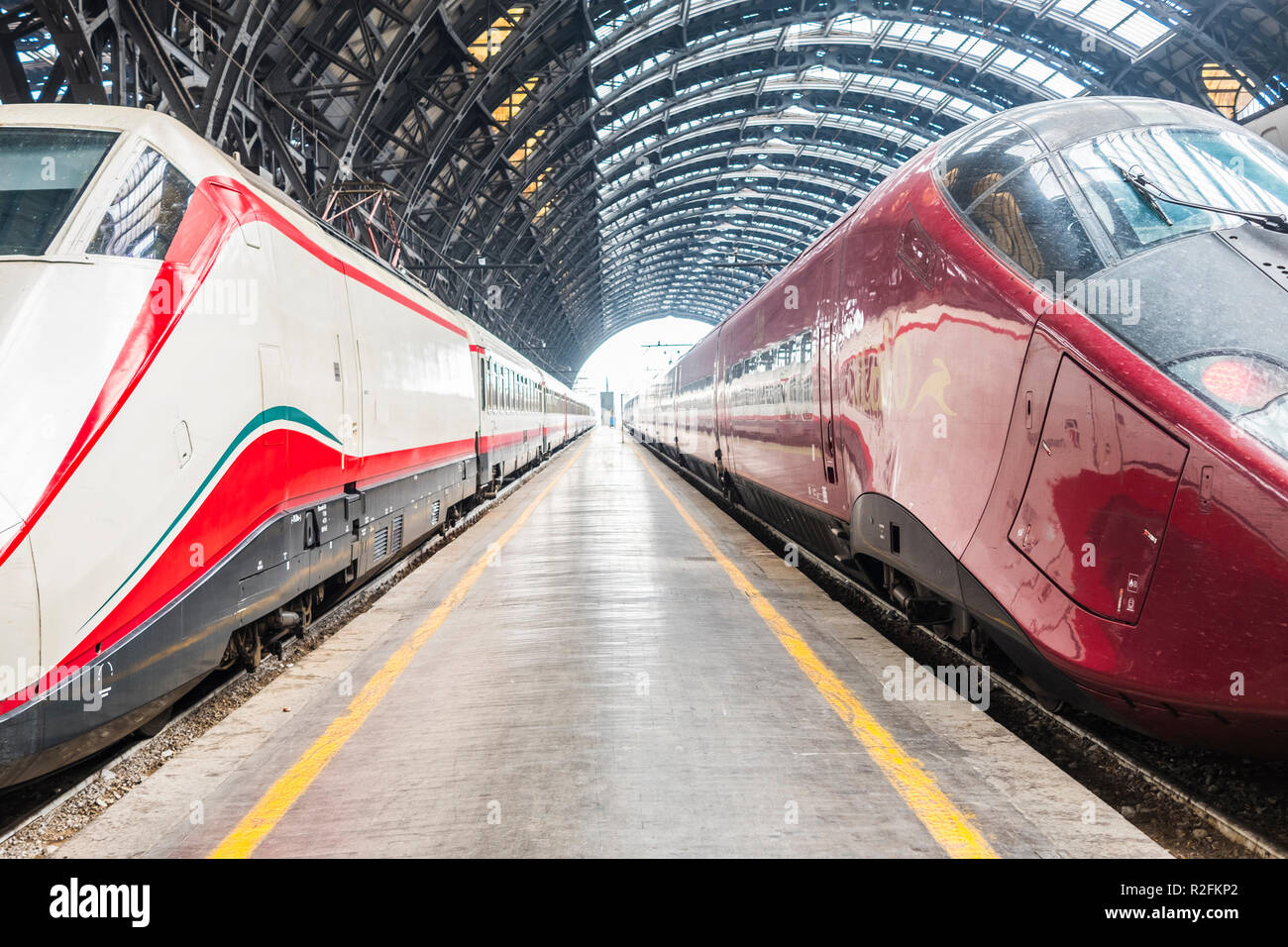 Modern high speed red commuter train at the railway station at sunset ...
