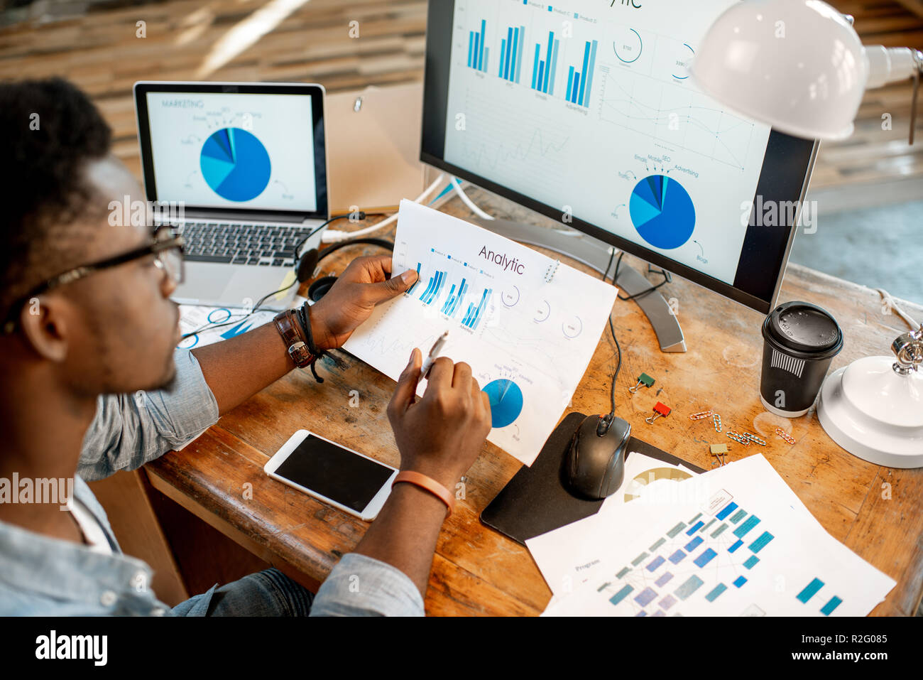 Young african man working with analitycs sitting at the beautiful ...