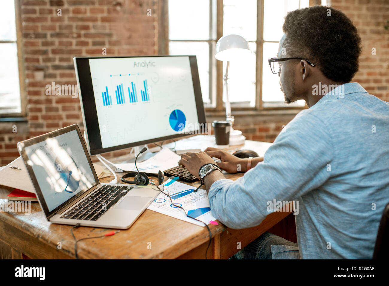 Young african man working with analitycs sitting at the beautiful ...