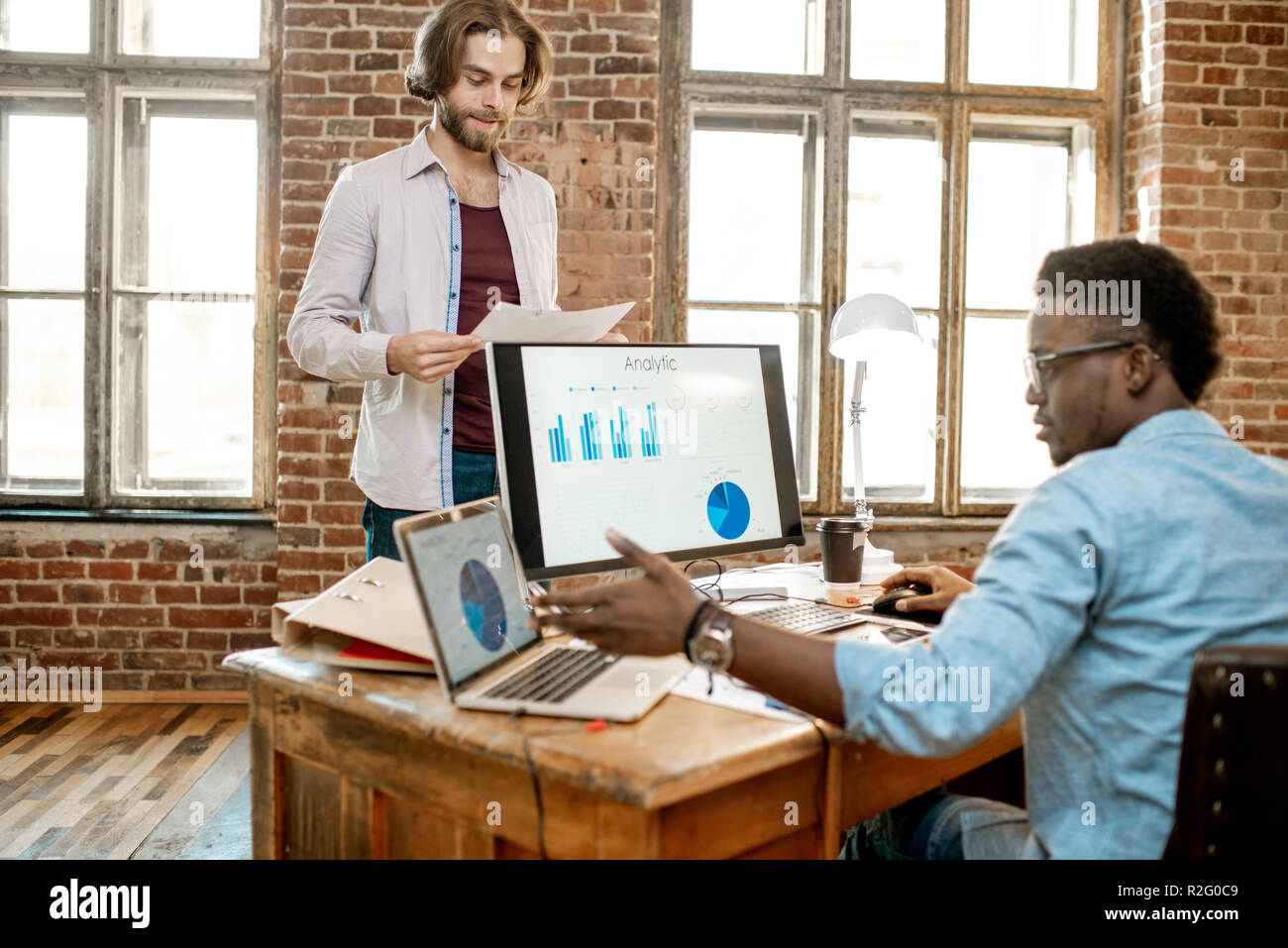 Two male coworkers working with analitycs in the beautiful office with ...