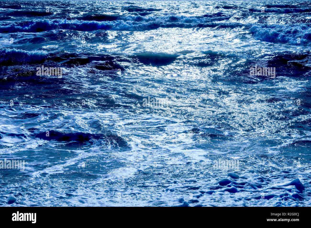 A dark blue sea with waves swelling the sea has dark shadows where the ...