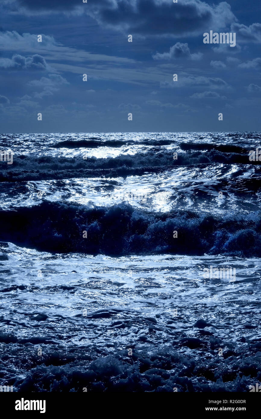 A dark blue sea with waves swelling the sea has dark shadows where the ...