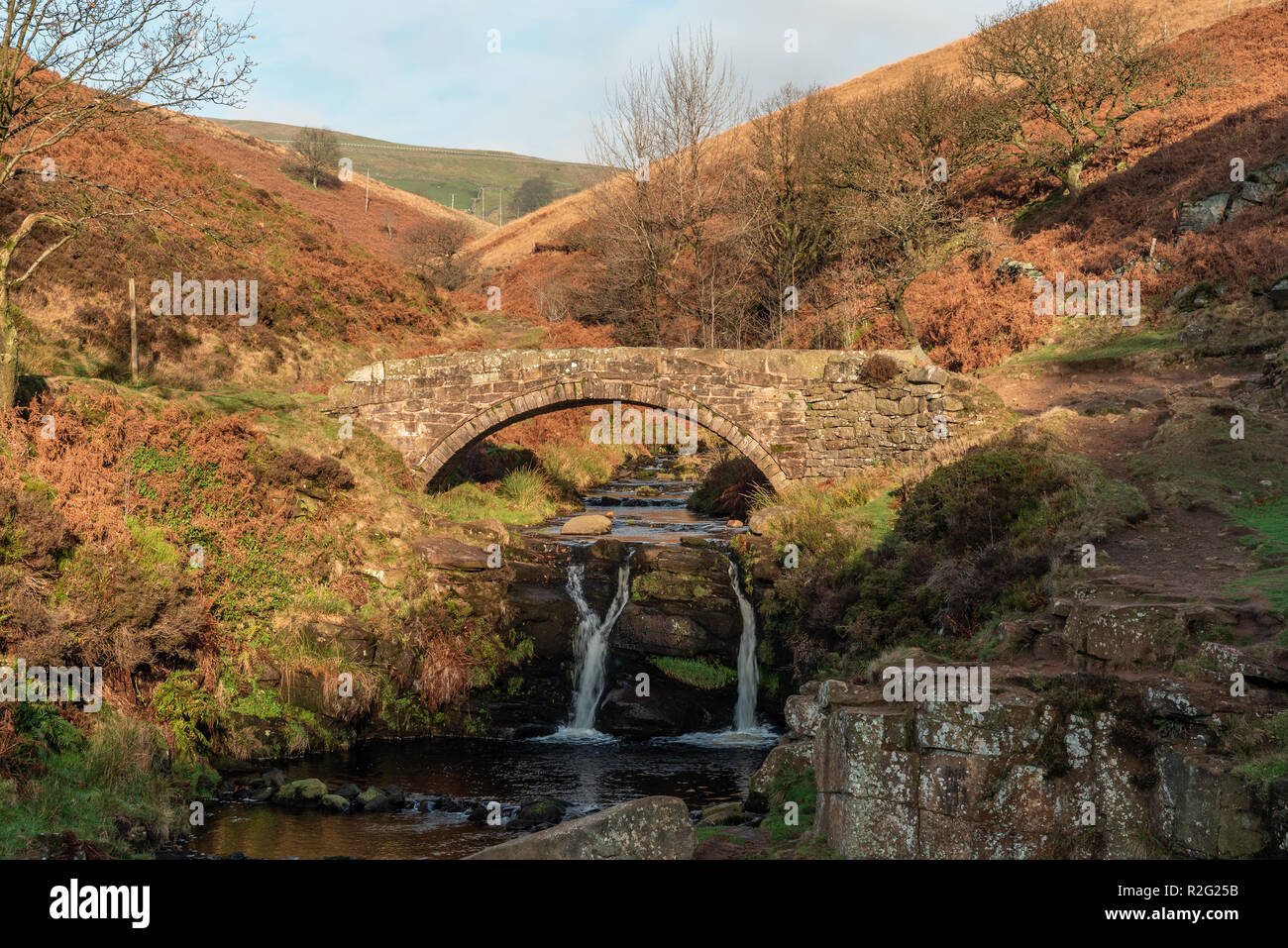 A waterfall and packhorse stone bridge at Three Shires Head in the Peak ...