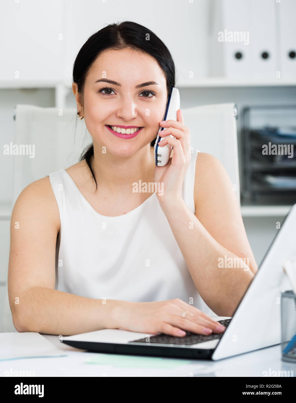 Woman employee having conversation on phone during work Stock Photo - Alamy
