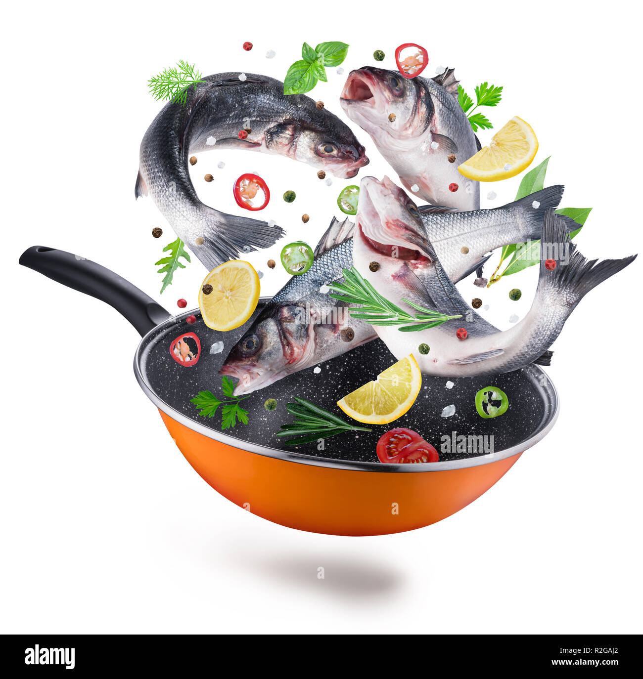 Flying seabass fishes and spices falling into a frying pan. Flying ...