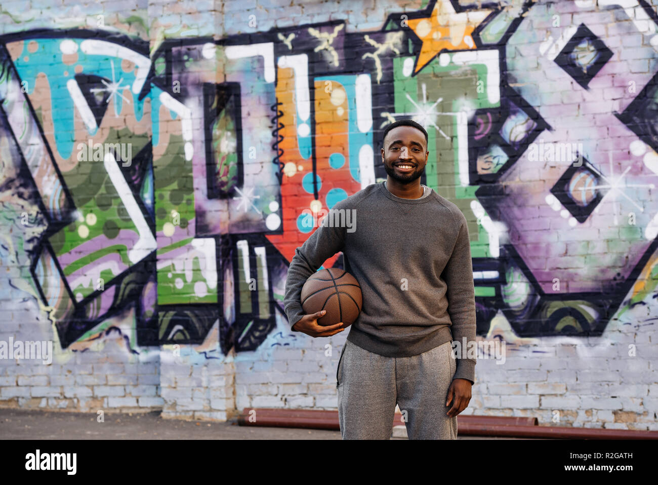 handsome african american man with basketball ball looking at camera on ...