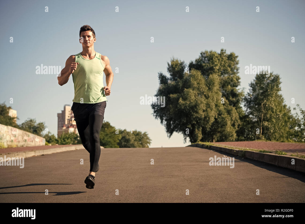 Man running on asphalt road on sunny summer day on blue sky. Success ...