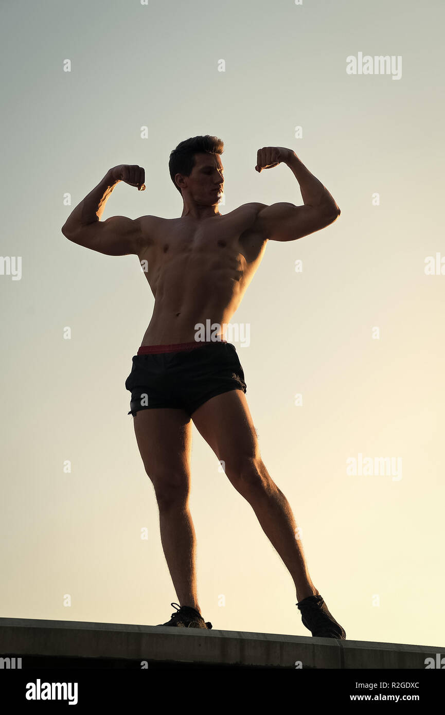 Man showing fit body on blue sky. Bodybuilder posing with muscular ...