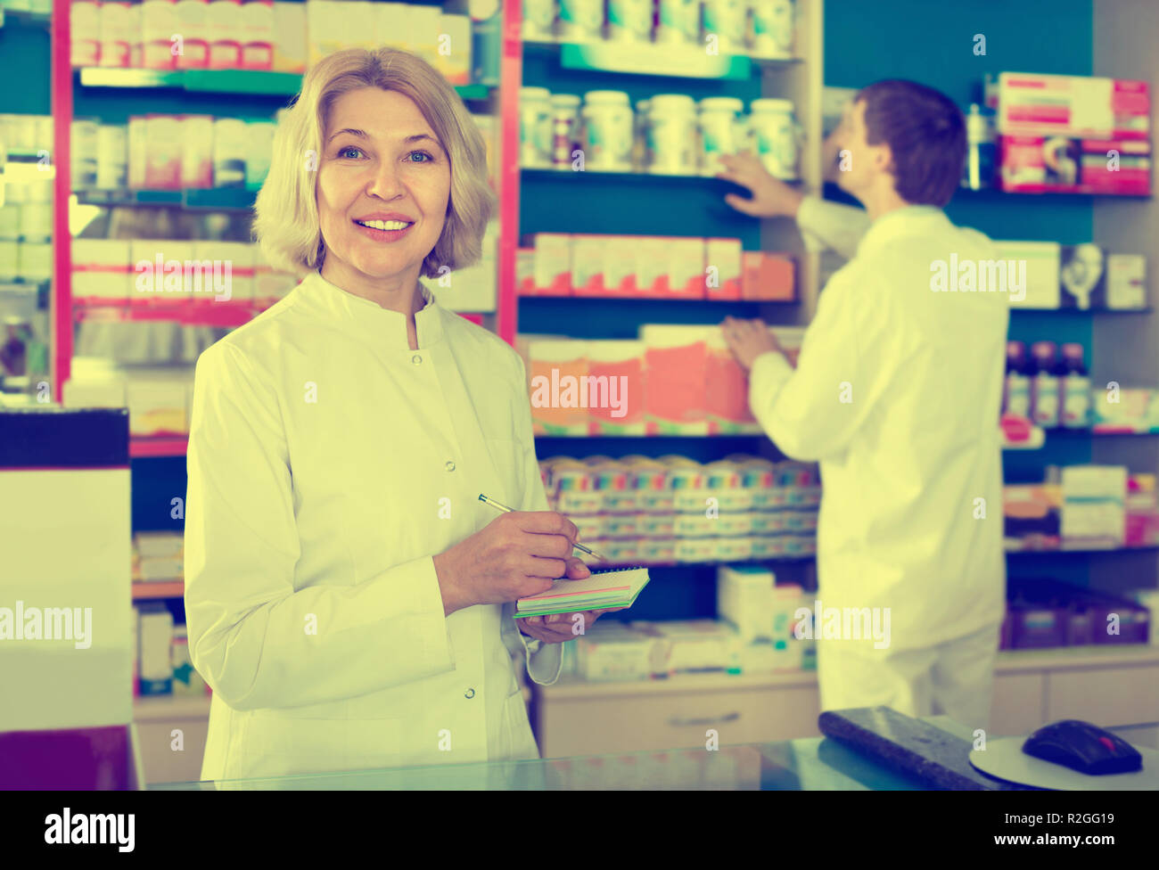 Portrait of two friendly cheerful smiling pharmacists working in modern ...