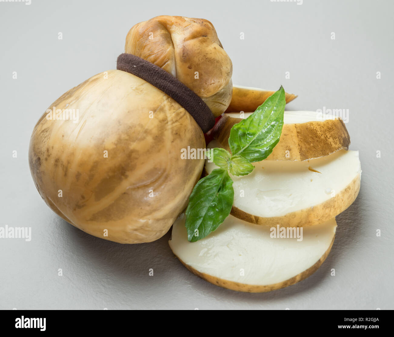 Traditional Italian smoked Scamorza cheese with herbs on gray ...
