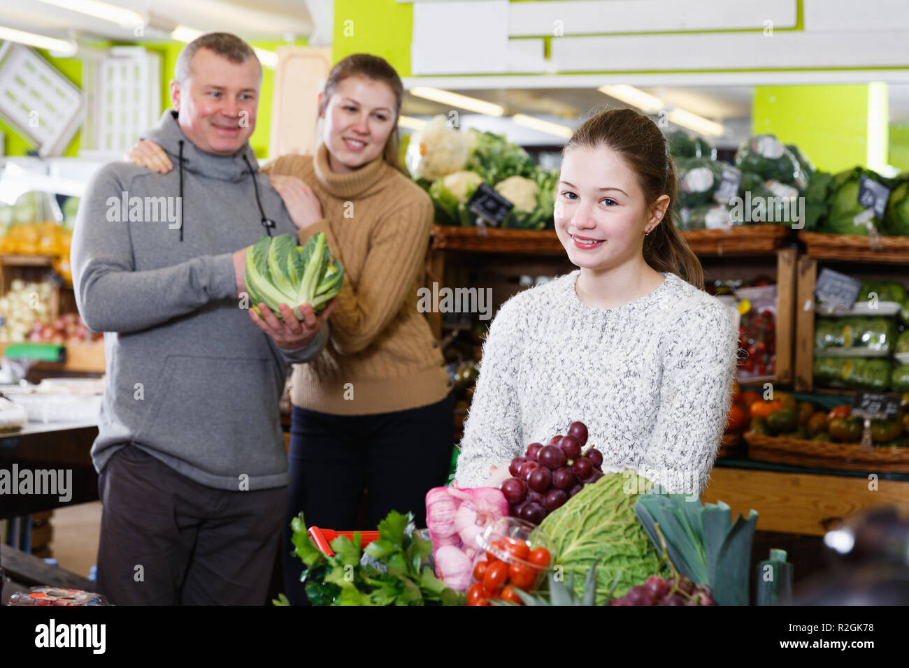 Happy little girl with loving parents choosing fresh fruits and ...