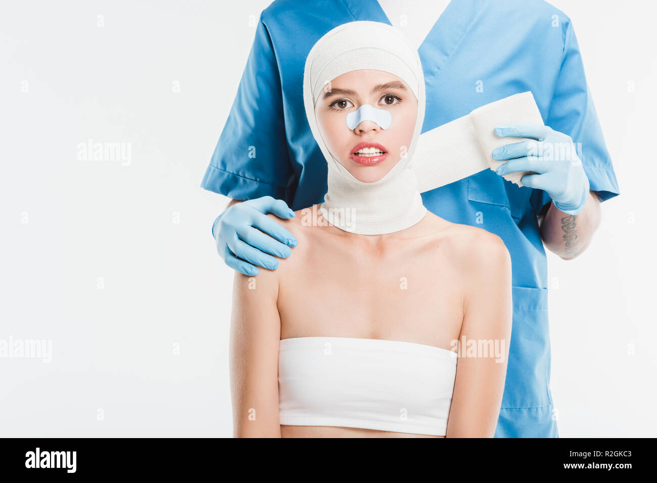 surgeon in gloves taping up woman face with bandage after plastic ...
