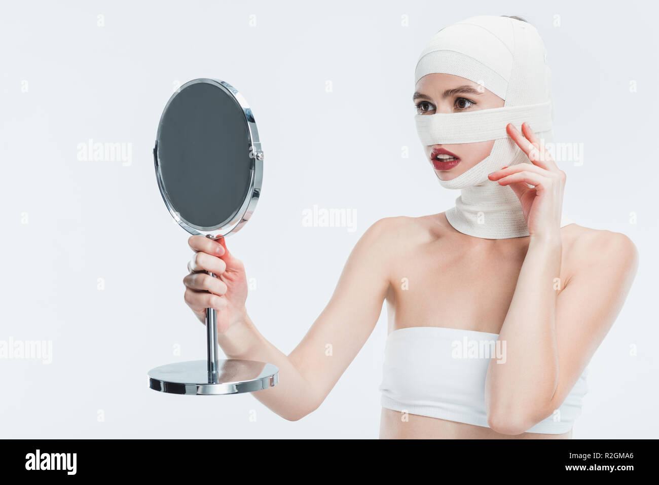 woman with bandages over head looking at mirror isolated on white Stock ...