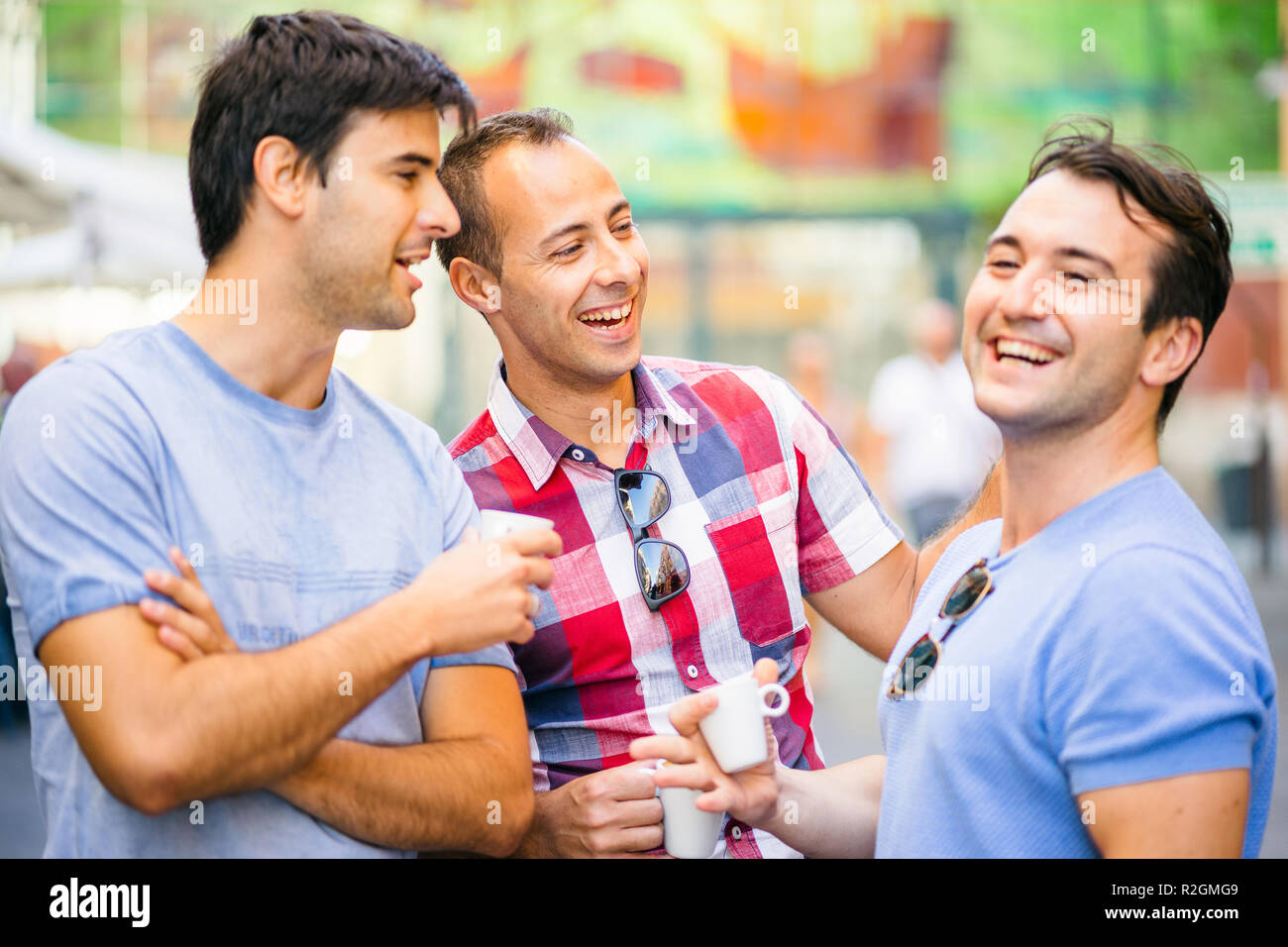 Three friends talking and having fun while drinking a coffee outdoor ...