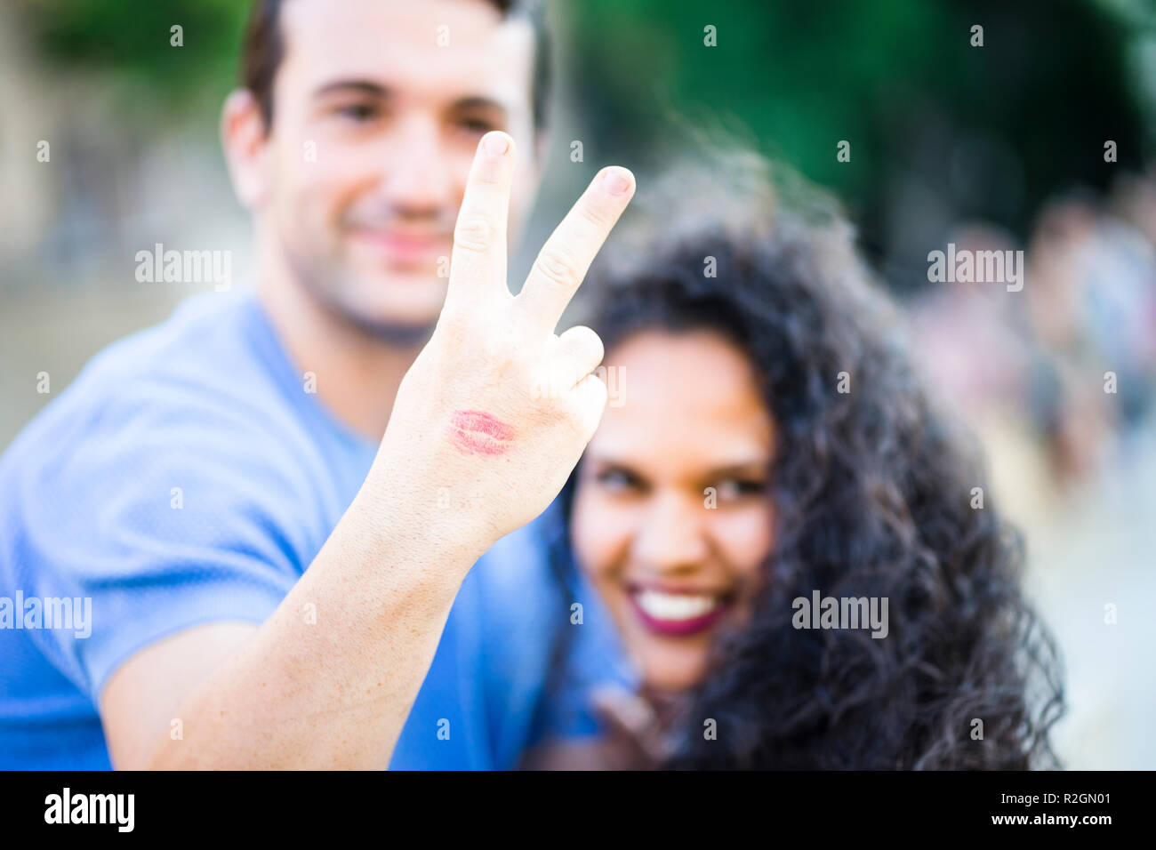 Happy young couple showing peace sign with visible lipstick print on ...