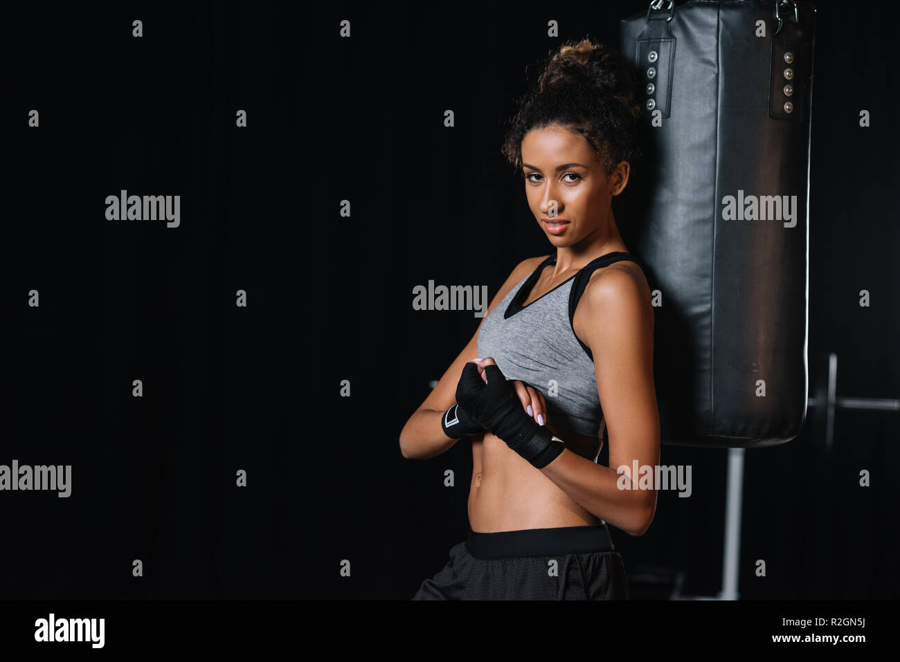 african american female boxer in boxing bandage posing near punching ...