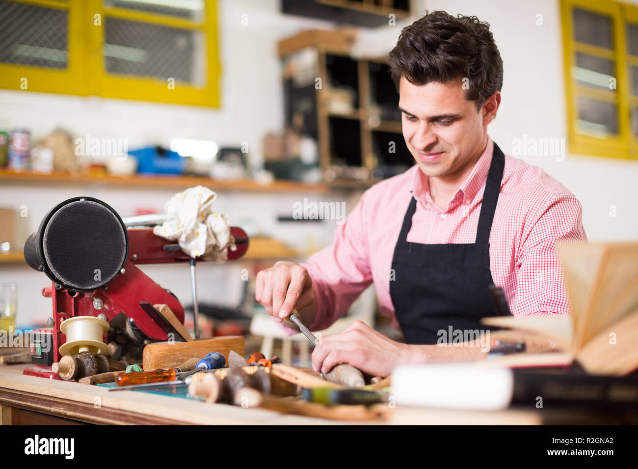 Skilled concentrated joiner working in workshop with chisel in hands ...