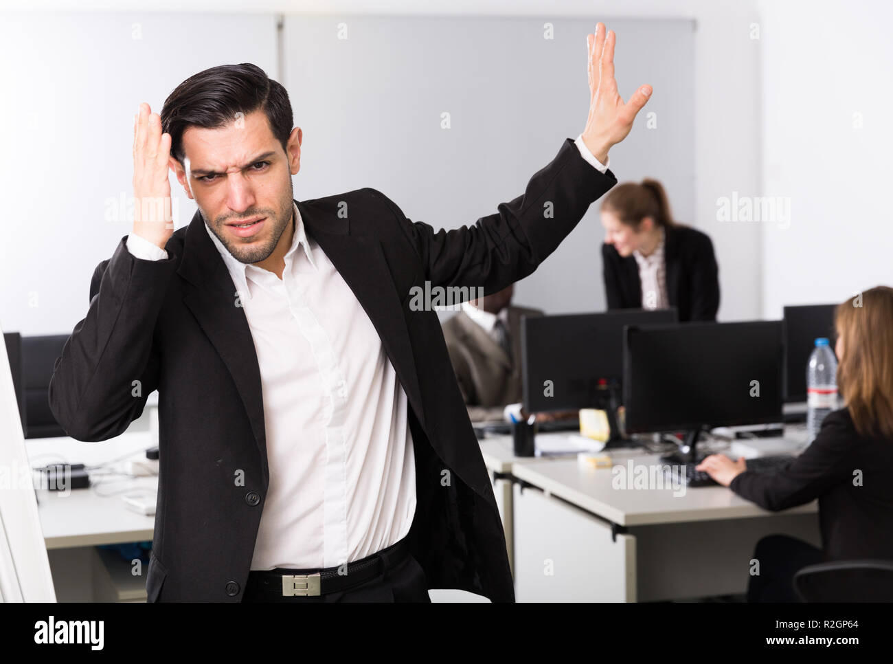 Irritated businessman standing in modern office on background of ...