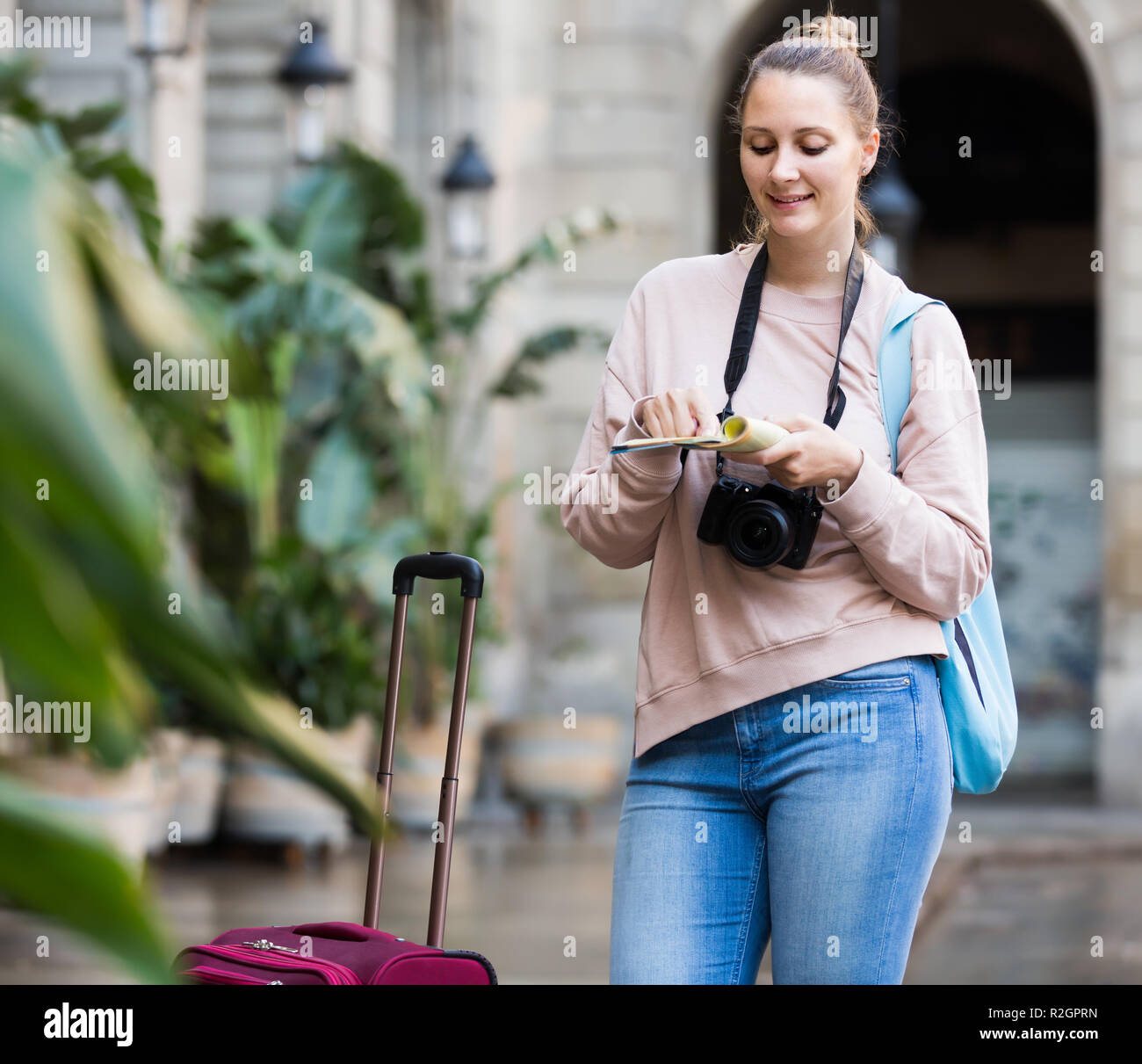 Brunette traveling girl searching for the direction using a booklet in ...