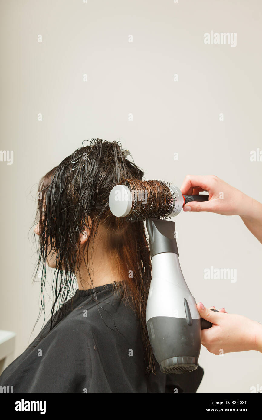 Hairdresser drying dark female hair using professional hairdryer, heat ...