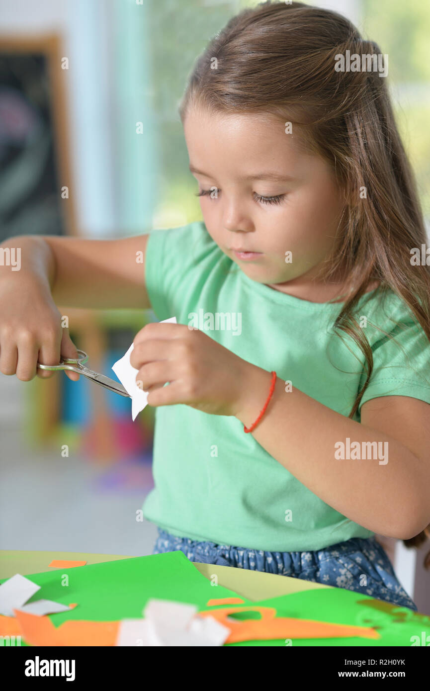 Portrait of cute llittle girl is cutting color paper Stock Photo - Alamy