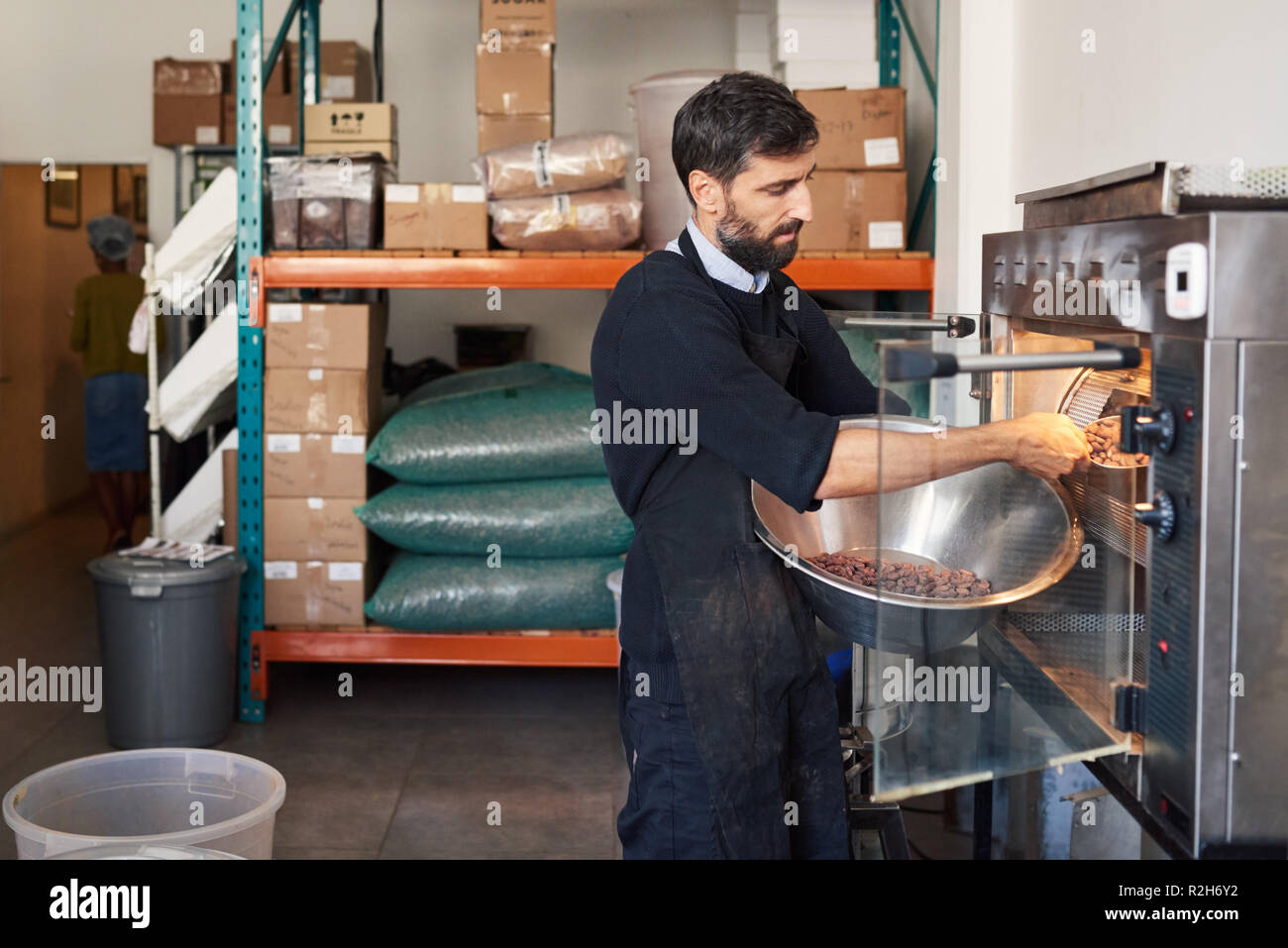 Worker roasting cocoa beans in an artisanal chocolate making factory ...