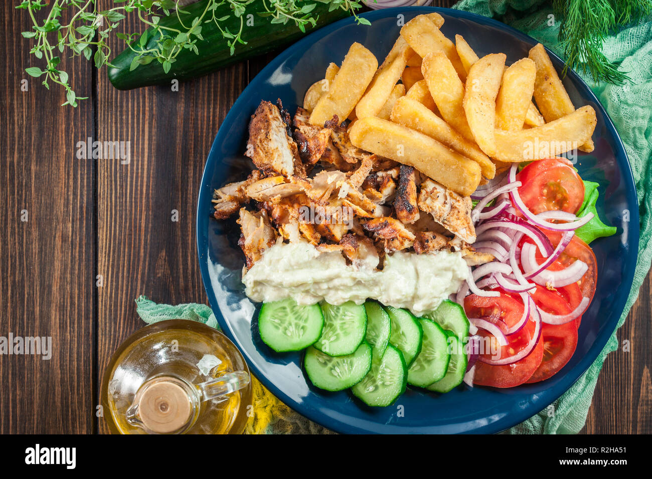 Greek gyros dish with french fries and vegetables. Served with tzatziki ...
