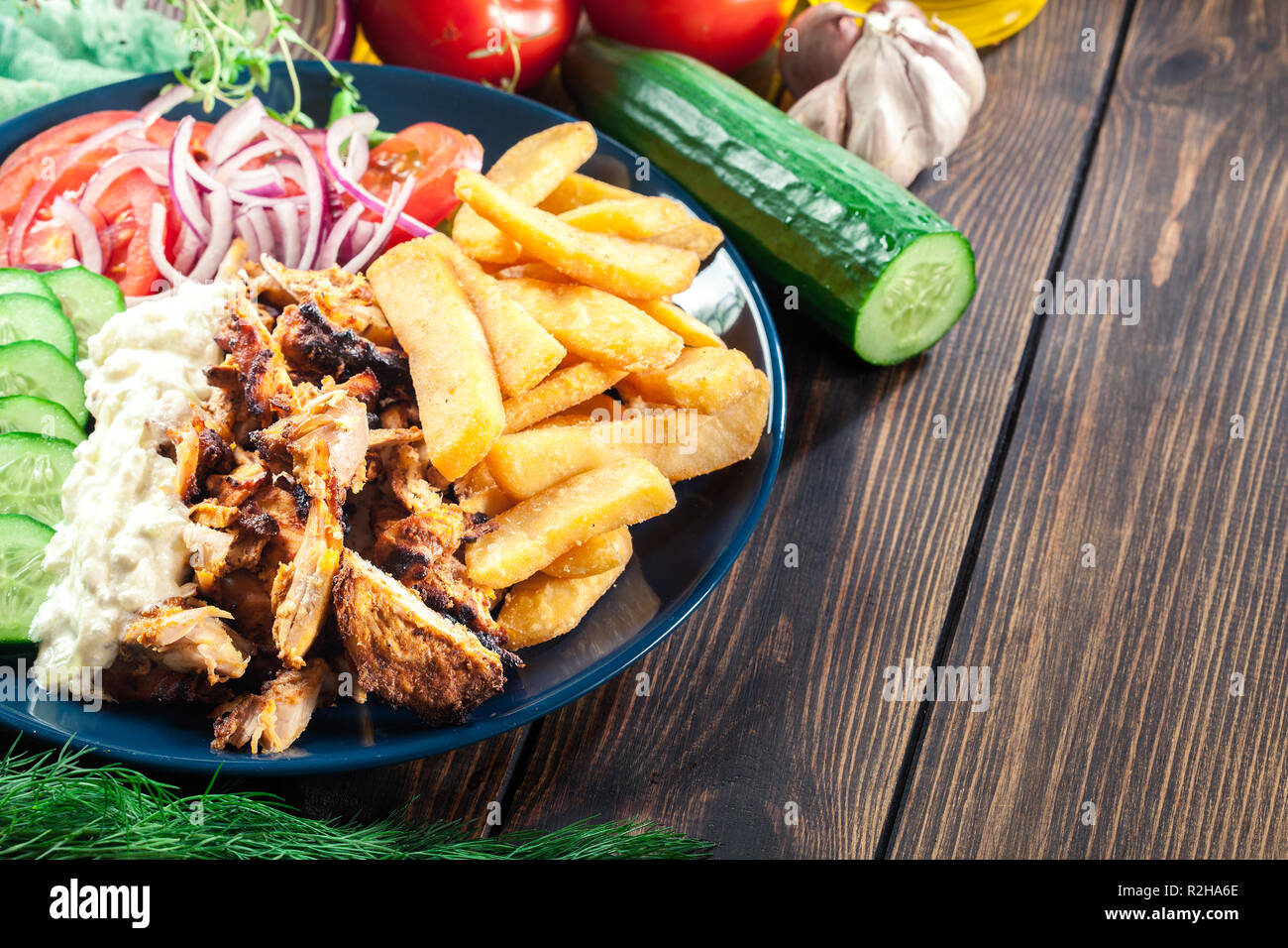 Greek gyros dish with french fries and vegetables. Served with tzatziki ...