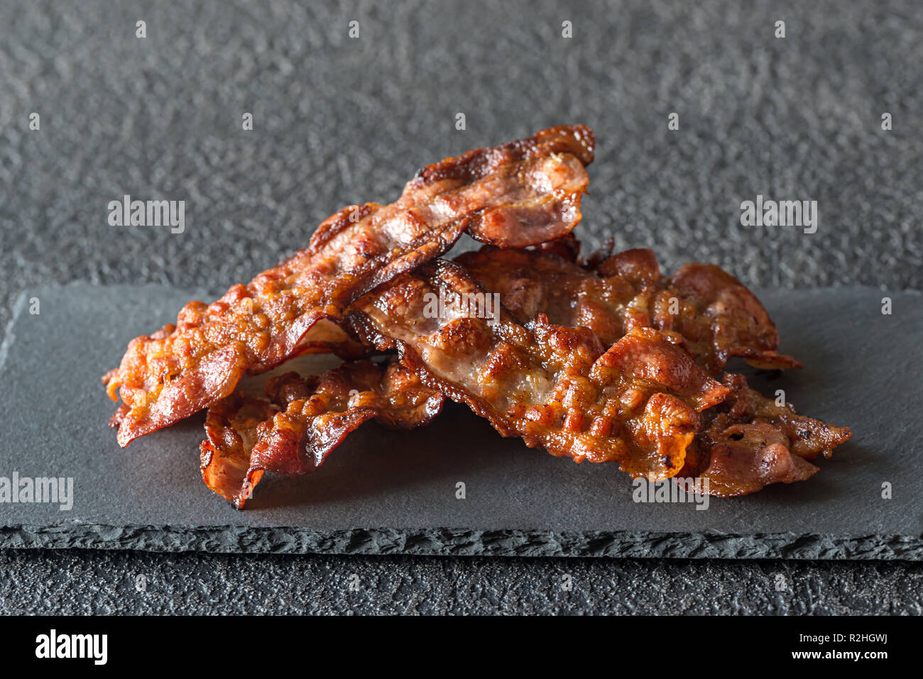 Fried bacon strips on the stone dark board Stock Photo - Alamy
