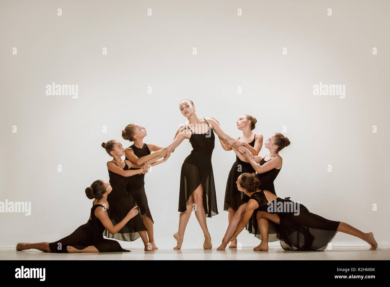 The group of modern ballet dancers dancing on gray studio background ...
