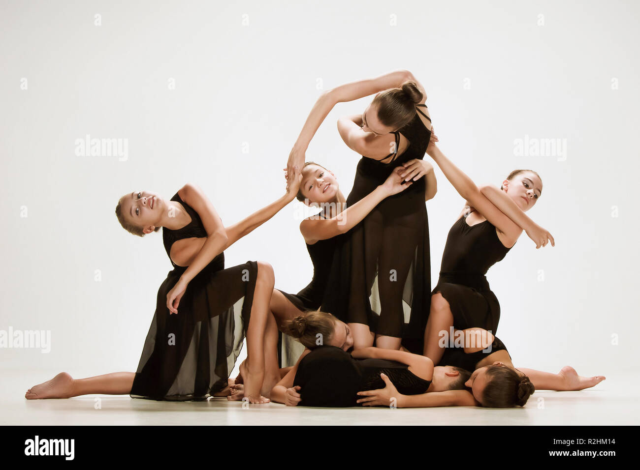 The group of modern ballet dancers dancing on gray studio background ...