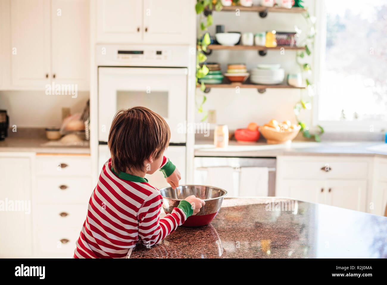 Boy leaning on kitchen counter stirring baking mixture Stock Photo - Alamy