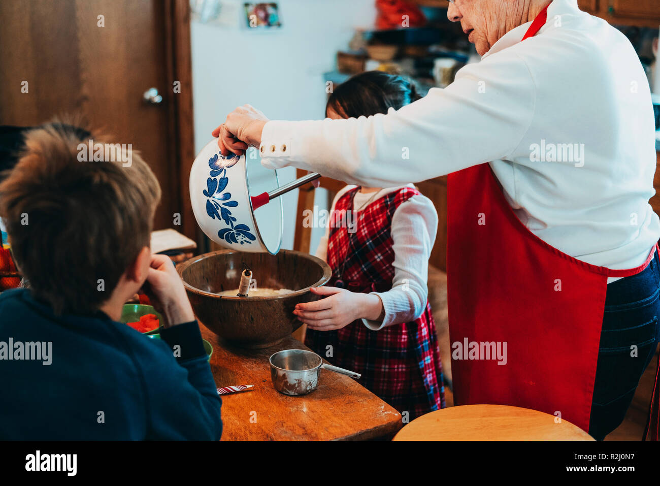 Two children helping their grandmother bake a cake Stock Photo - Alamy