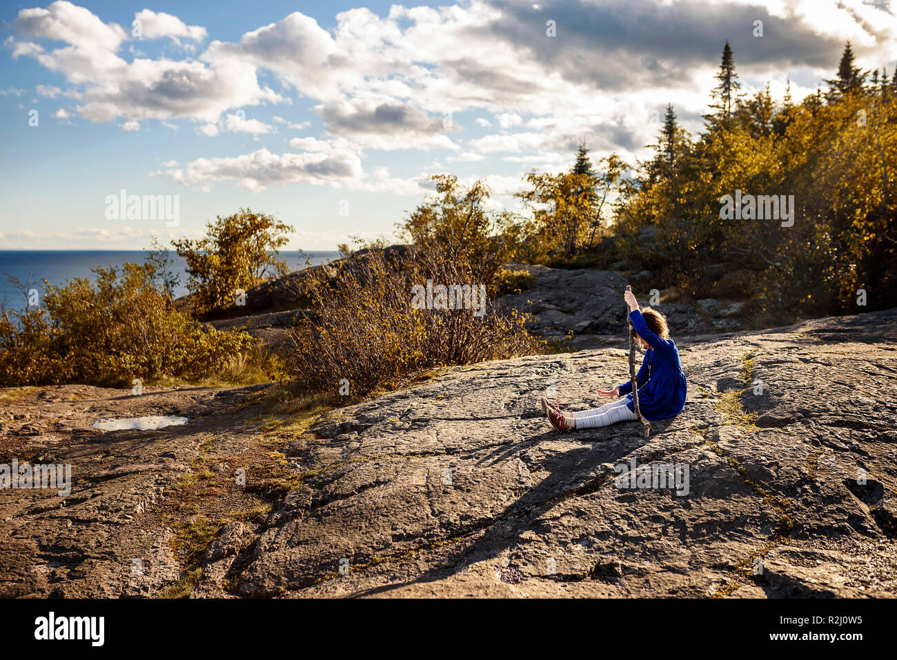 Girl sitting on rocks holding a stick, Lake Superior Provincial Park ...