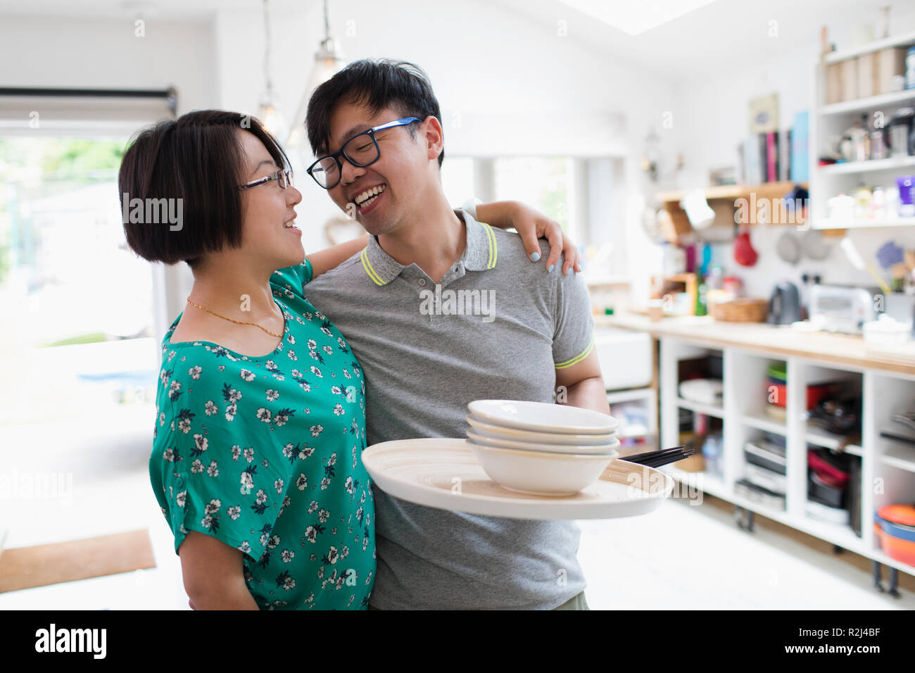 Affectionate couple hugging, doing dishes in kitchen Stock Photo - Alamy