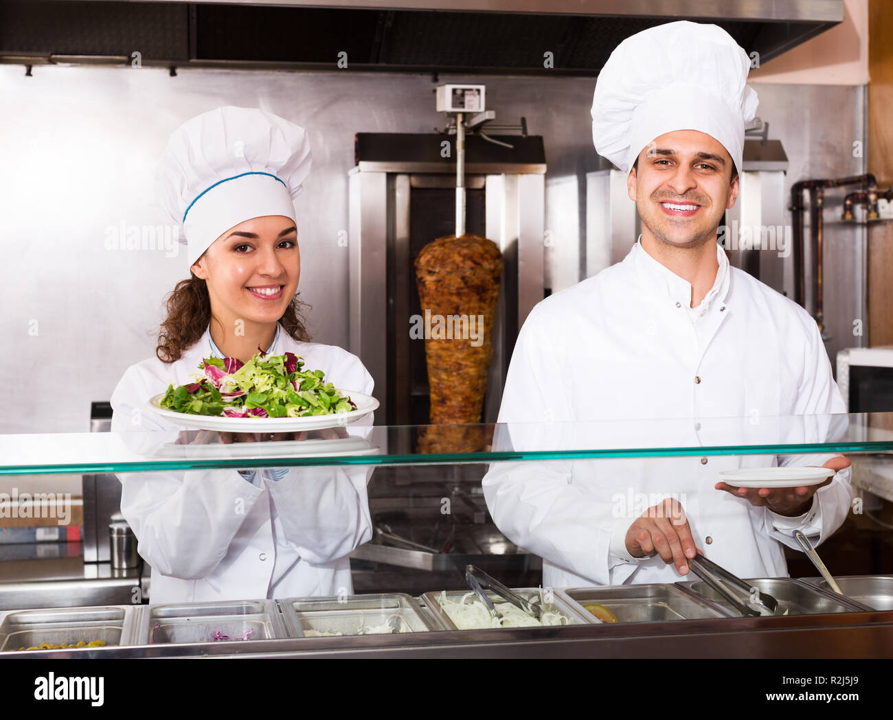 Pretty adult cafe staff posing at kebab counter Stock Photo - Alamy