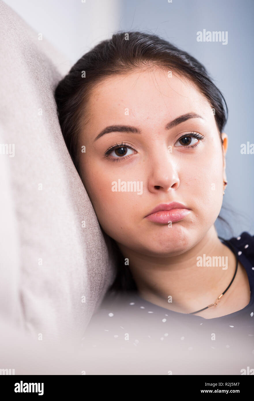 Young disappointed girl sitting on sofa at home Stock Photo - Alamy