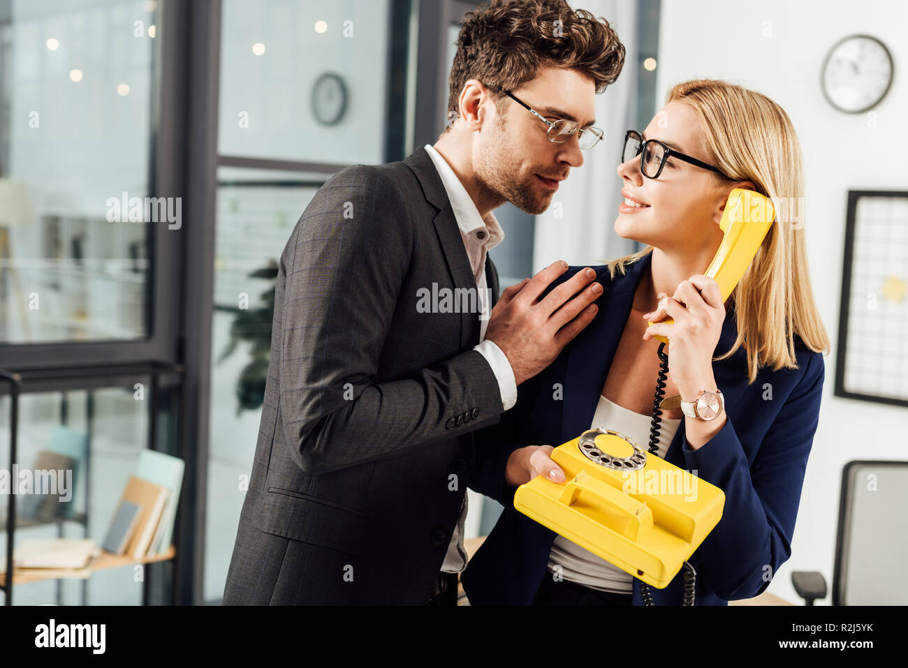 portrait of businessman flirting with young colleague with yellow retro ...