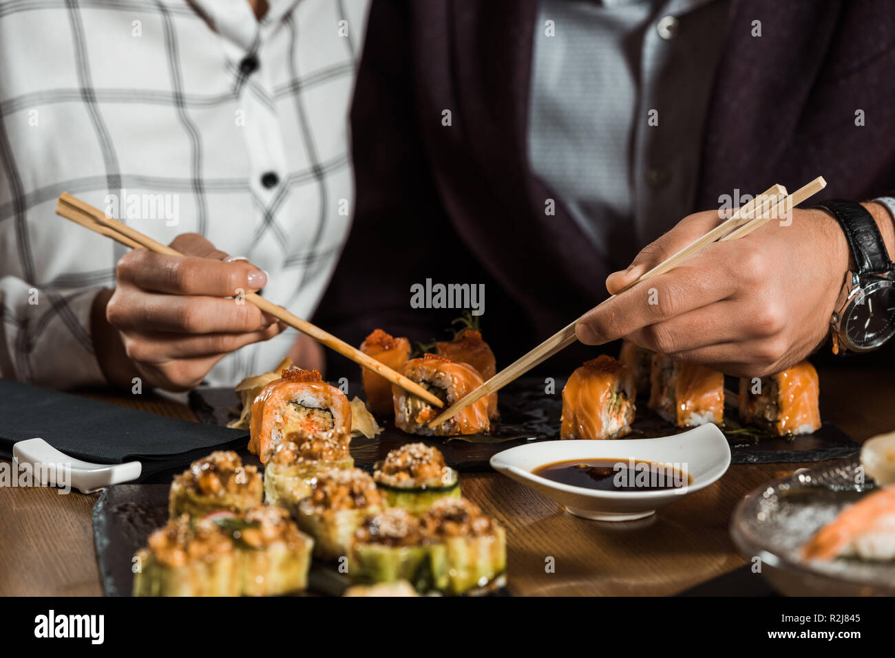 Partial view of people eating sushi rolls in restaurant Stock Photo - Alamy
