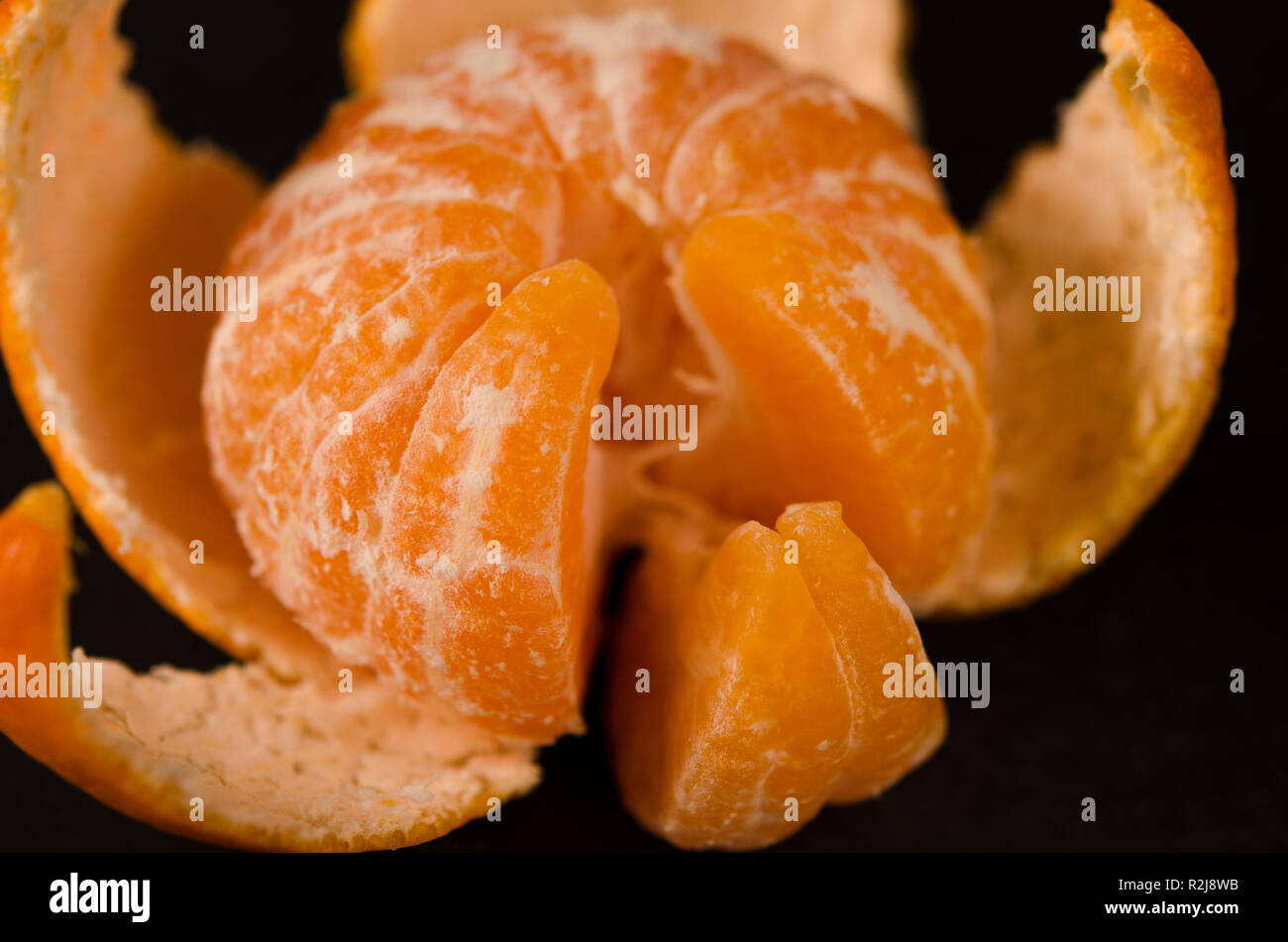 Juicy orange tangerine with skin and slices lies on the table of black ...
