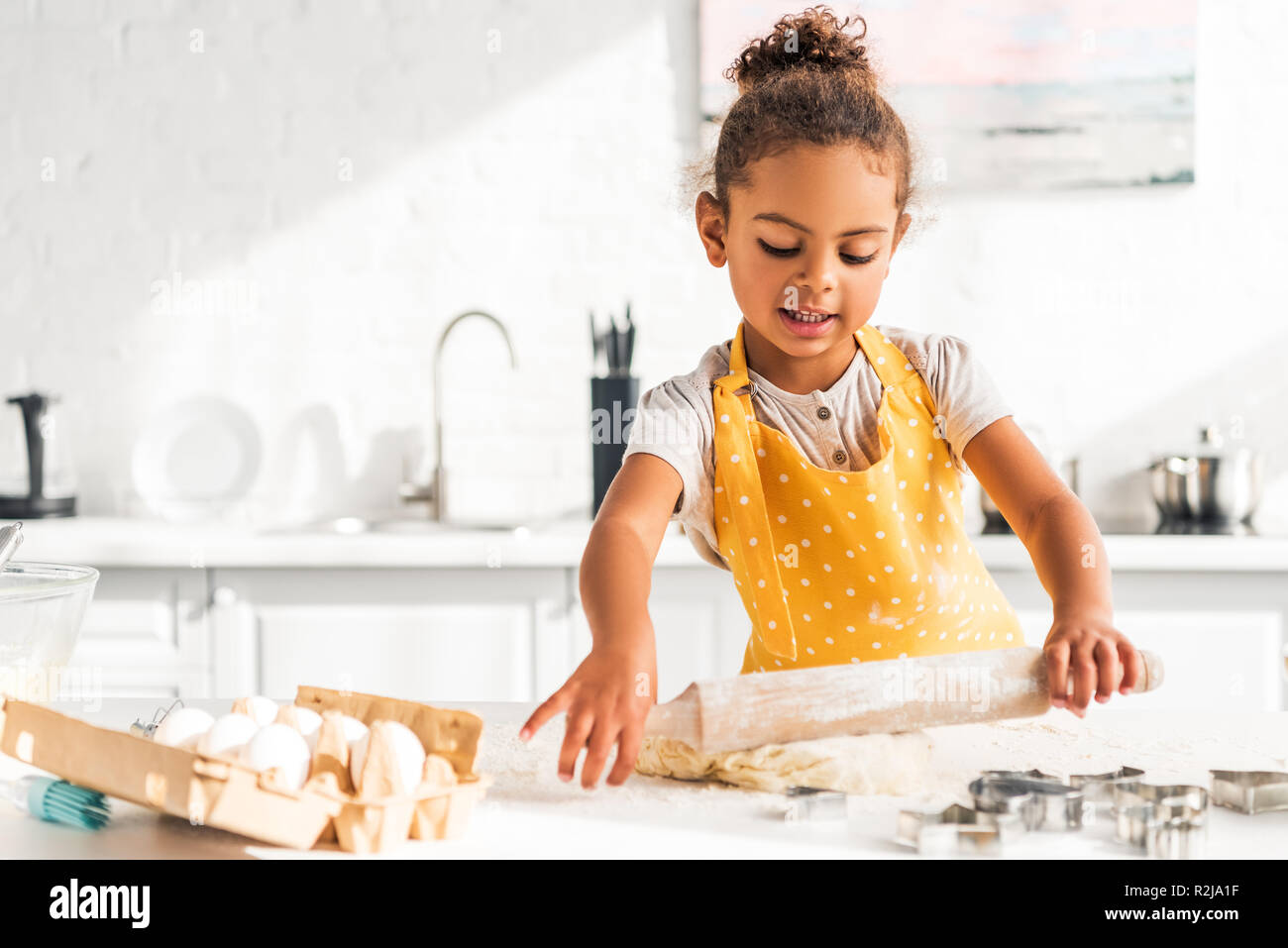 adorable african american child rolling dough with rolling pin in ...