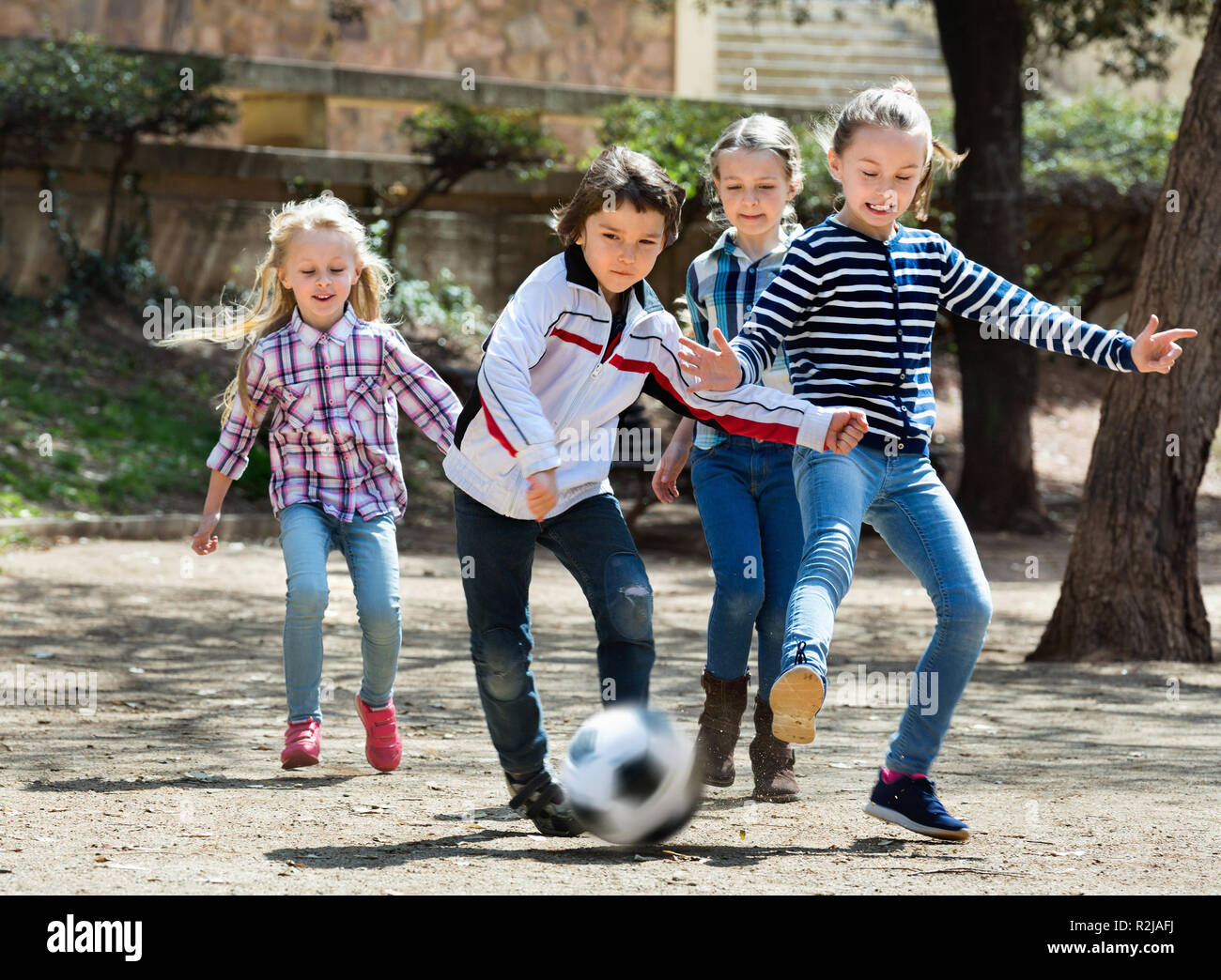 Group of cheerful children running after ball in urban location Stock ...
