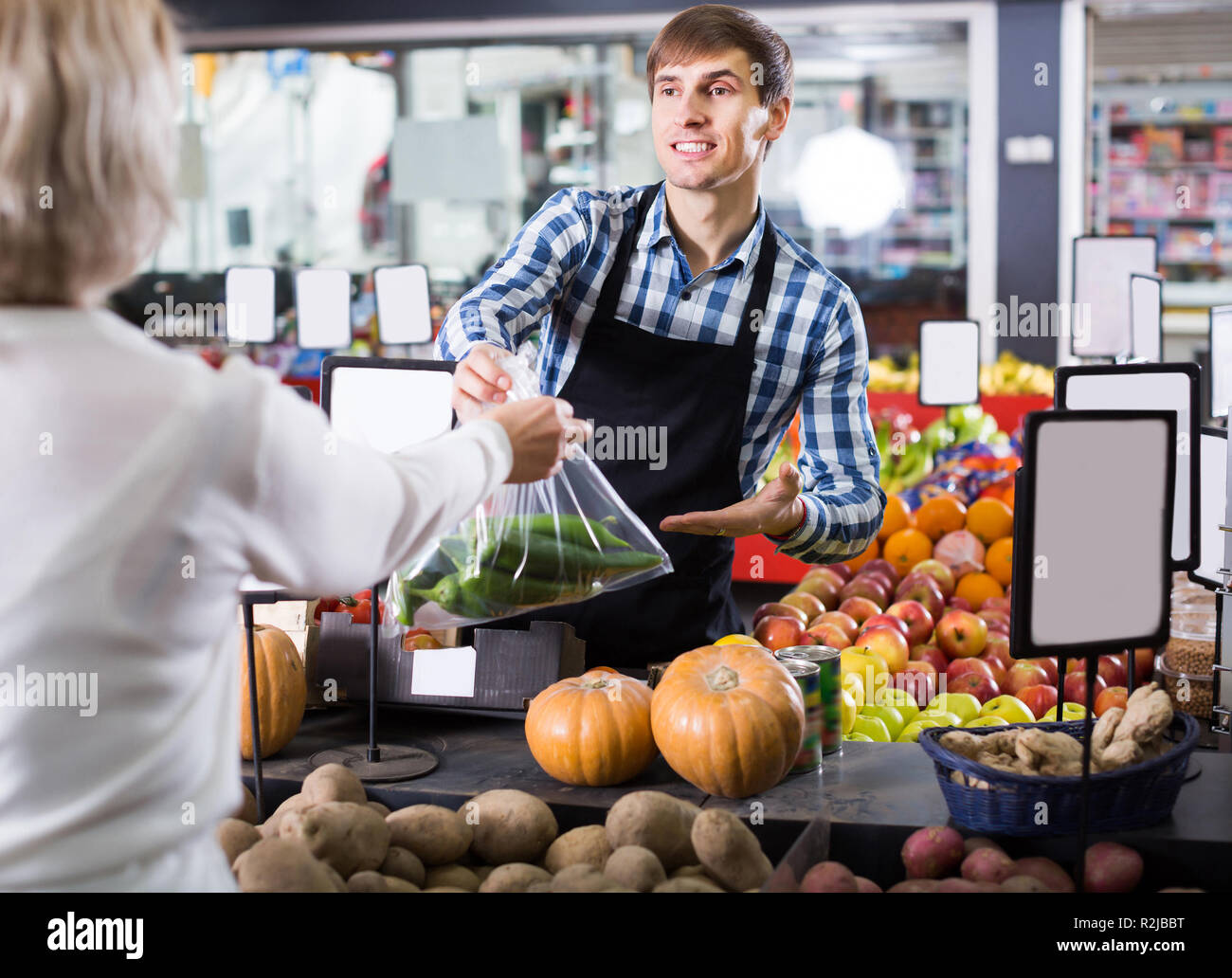 Happy employee of supermarket selling vegetables and fruits Stock Photo ...